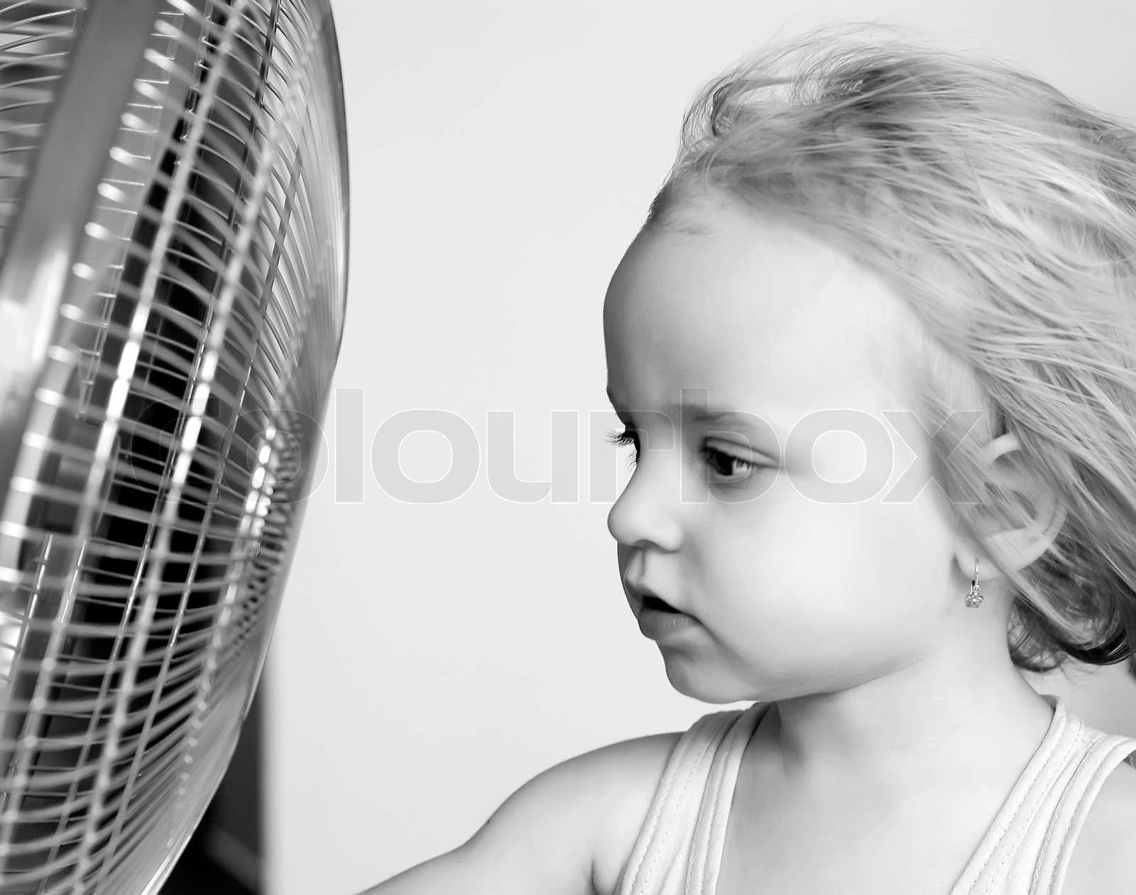 A little girl standing in front of fan | Stock image | Colourbox