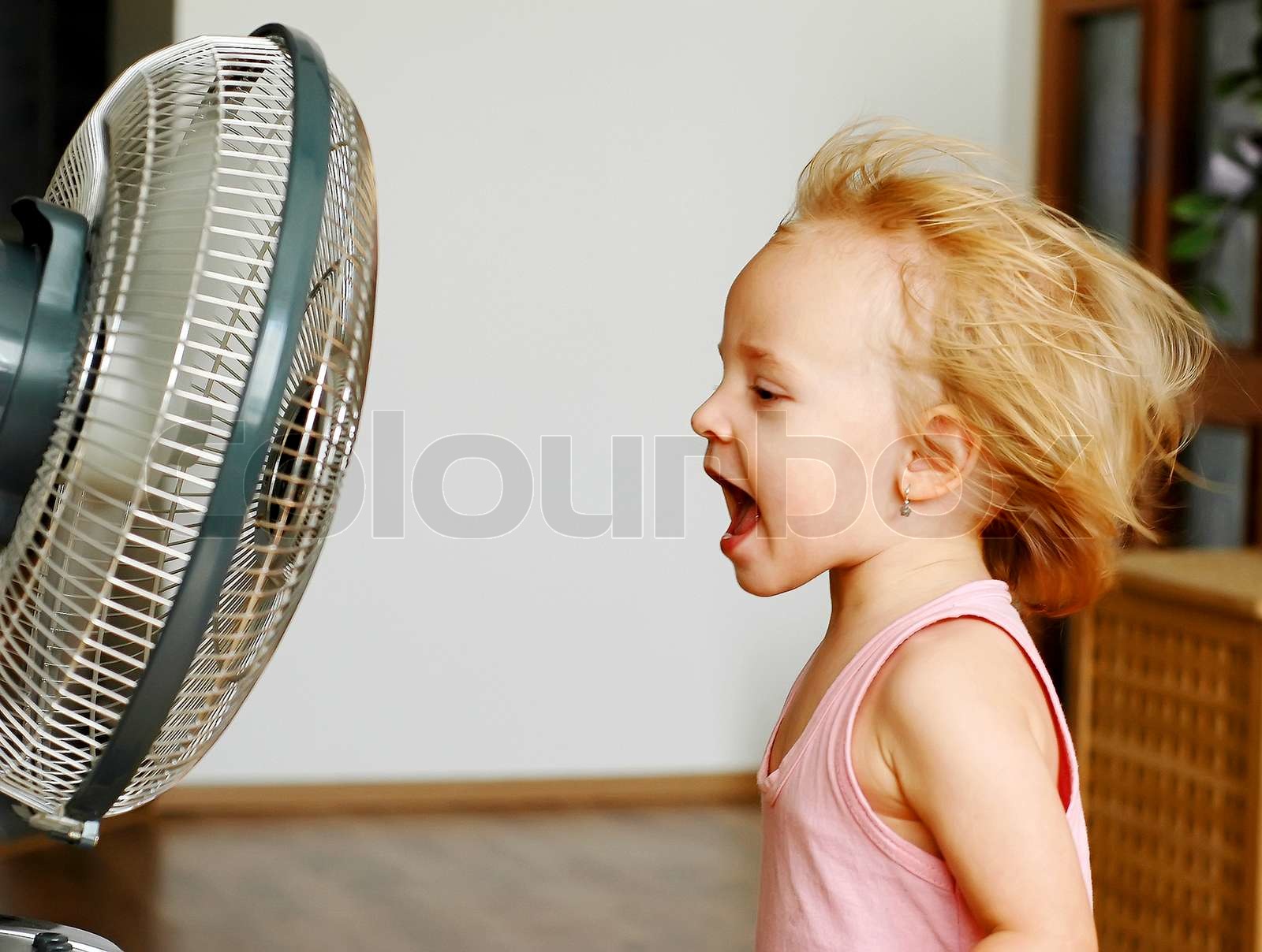 A little girl standing in front of fan | Stock image | Colourbox