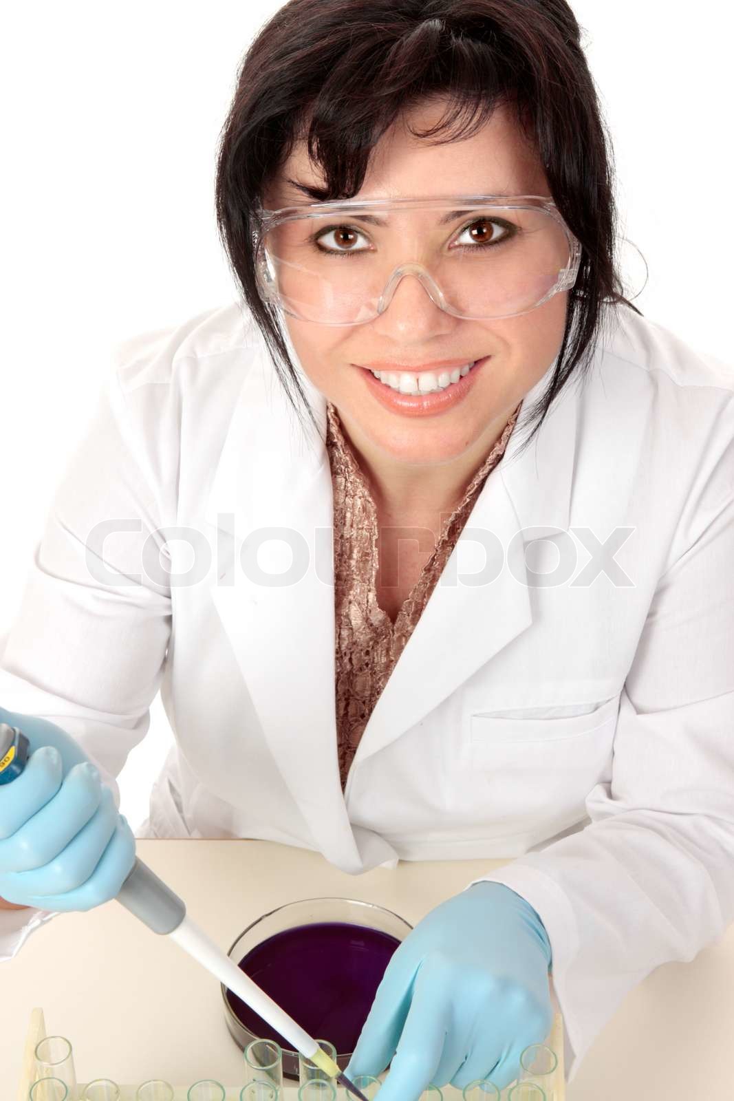 Smiling medical or scientific researcher sitting at desk with pipette ...