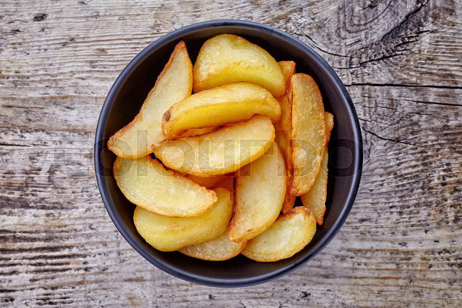 Bowl of potato wedges on wood, from above | Stock image | Colourbox