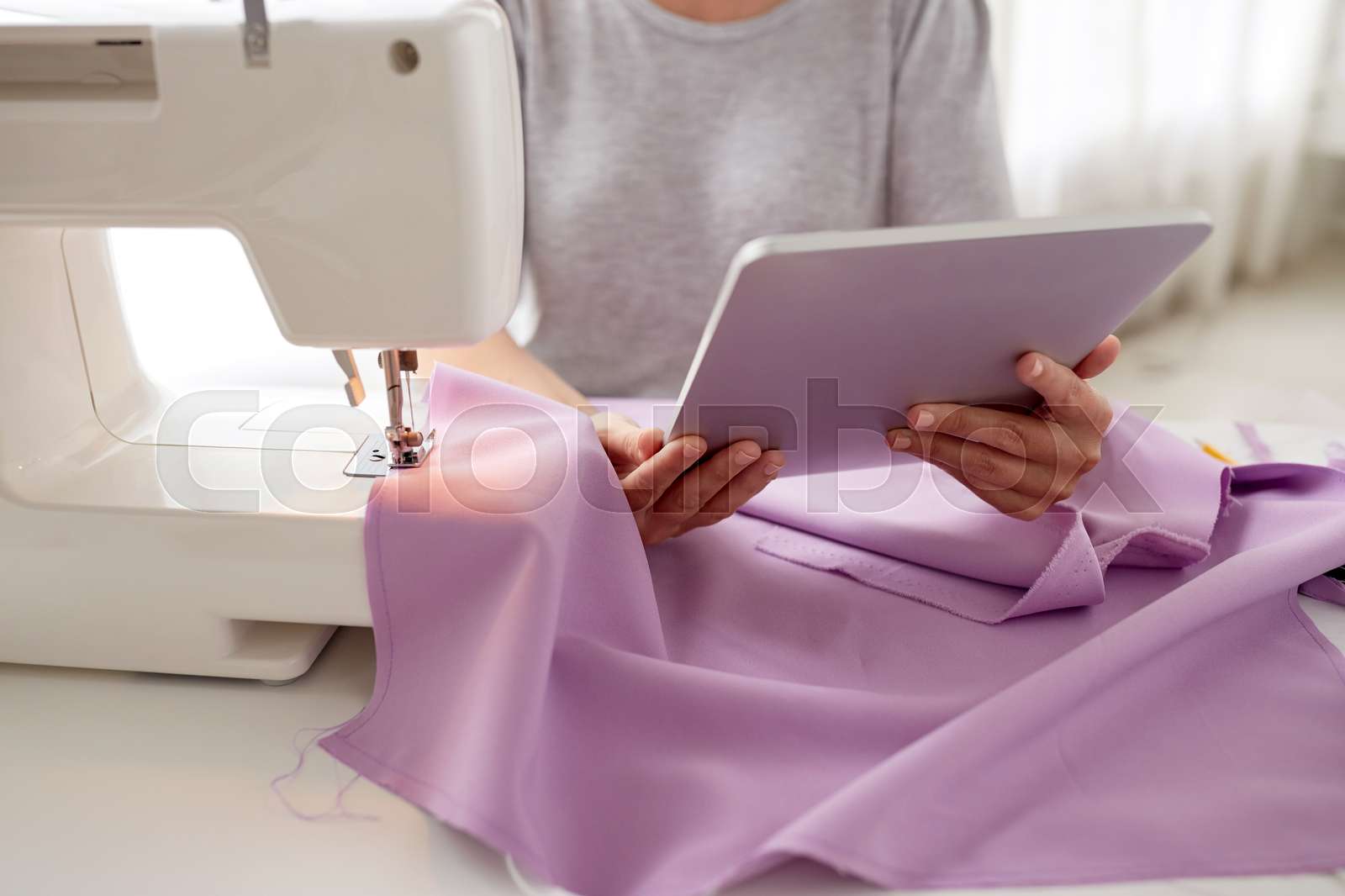 tailor with sewing machine, tablet pc and fabric | Stock image | Colourbox