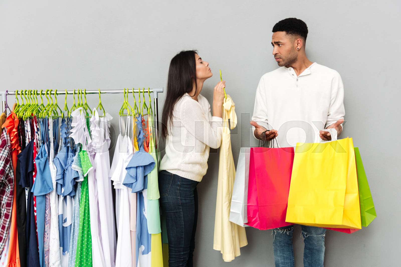 Lady begging clothes from confused man holding shopping bags. | Stock ...
