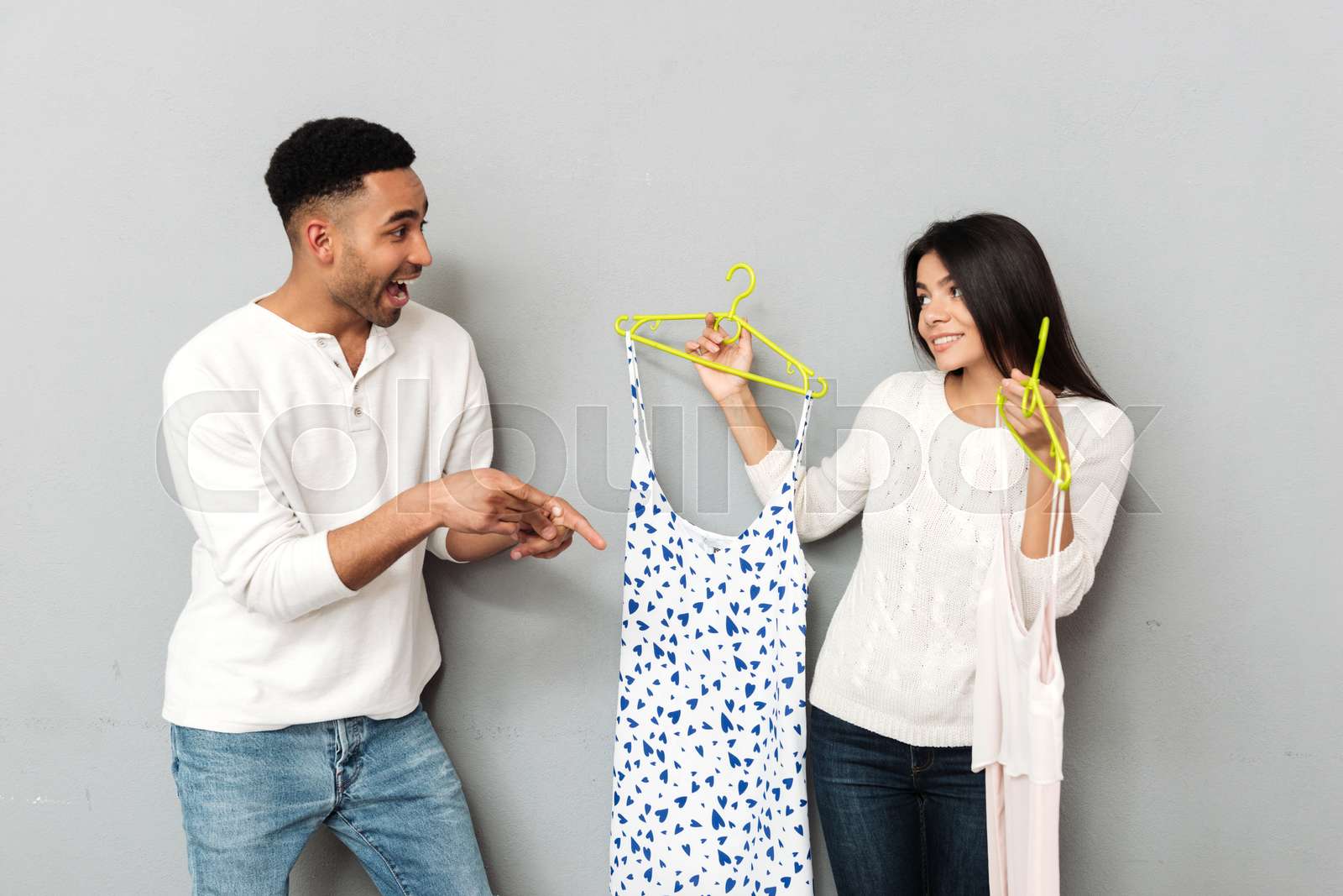 Young man choosing between two woman's dresses | Stock image | Colourbox