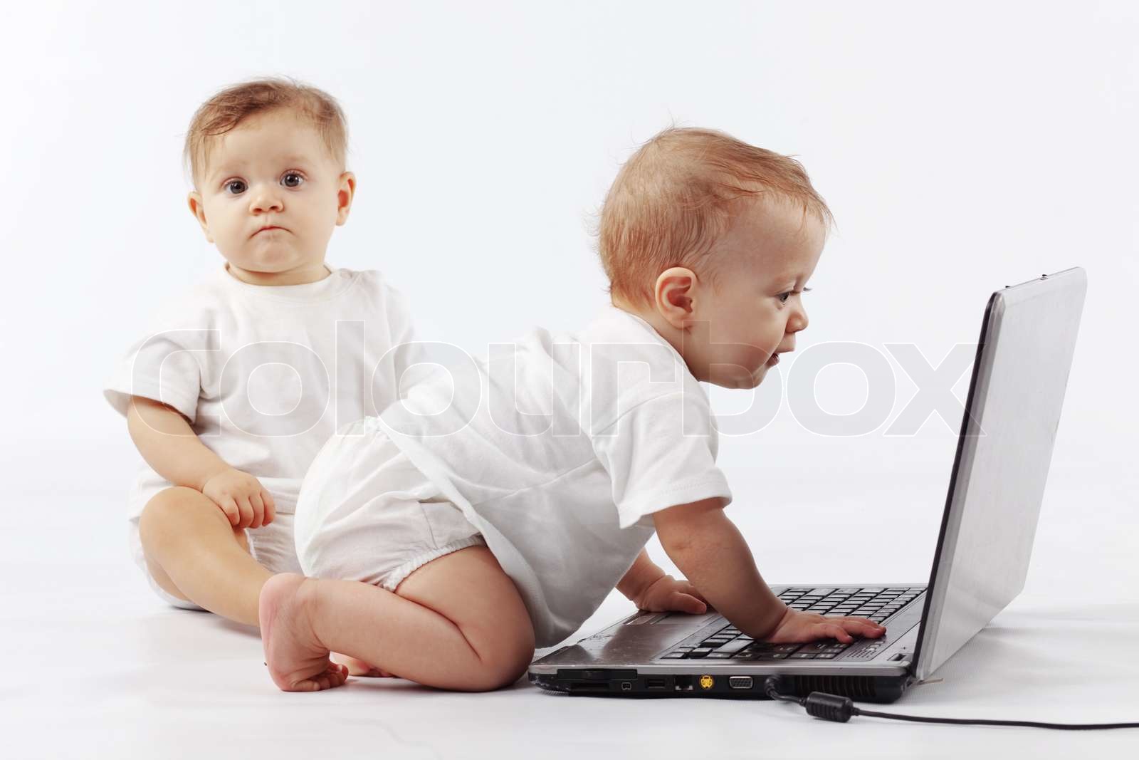 Two cute babies playing with laptop | Stock image | Colourbox