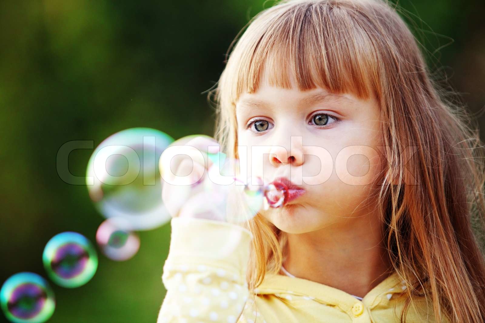 Portrait of funny lovely little girl blowing soap bubbles | Stock image ...