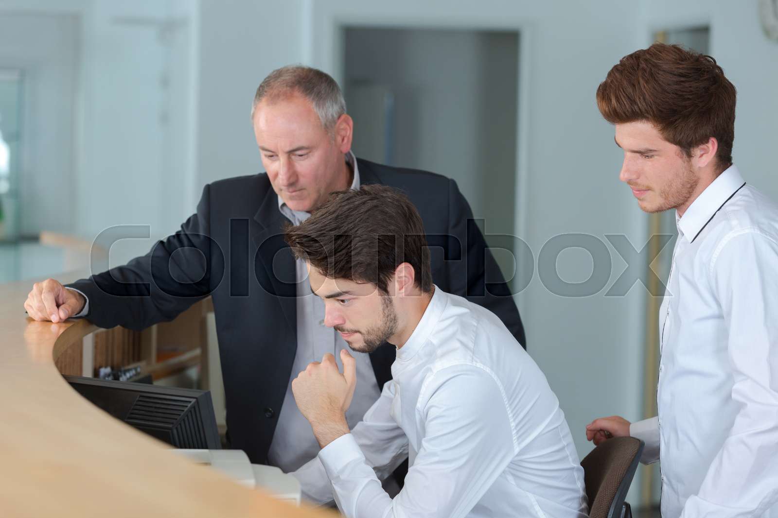 Men behind reception desk looking at computer | Stock image | Colourbox