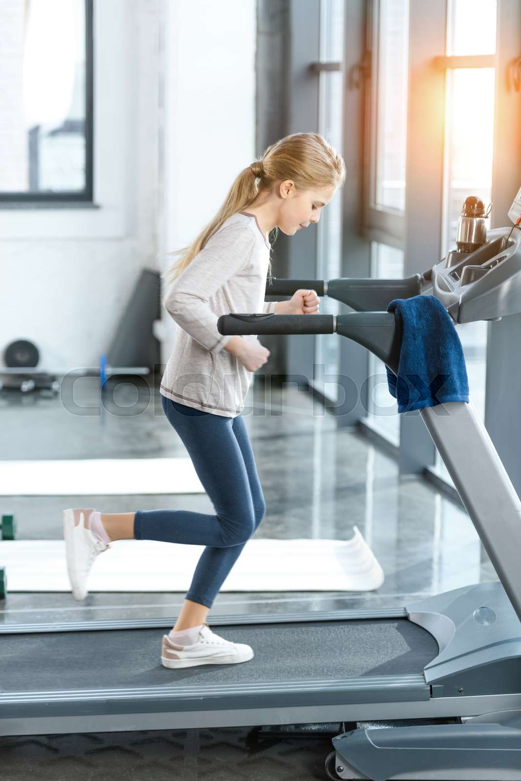 Blonde girl workout on treadmill, side view | Stock image | Colourbox