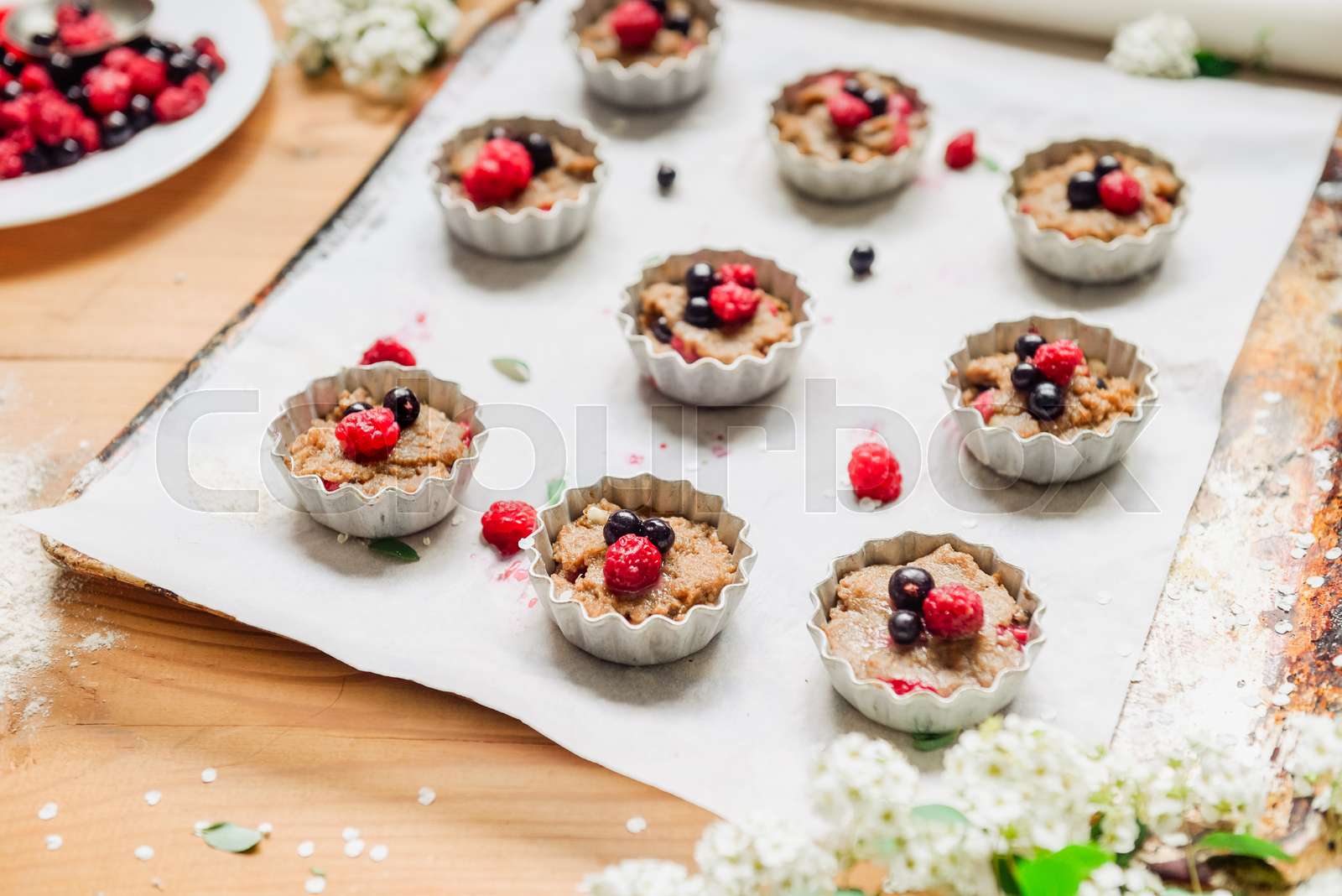 Raw dough with berries for cupcakes decomposed into forms on a baking ...