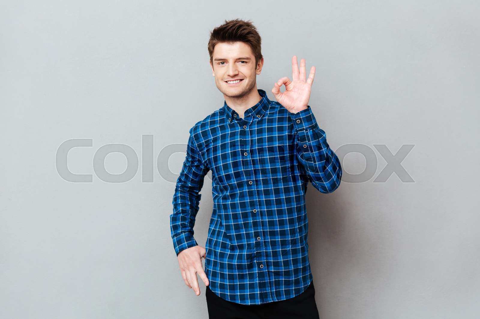 Happy man standing over grey wall and showing okay gesture | Stock ...