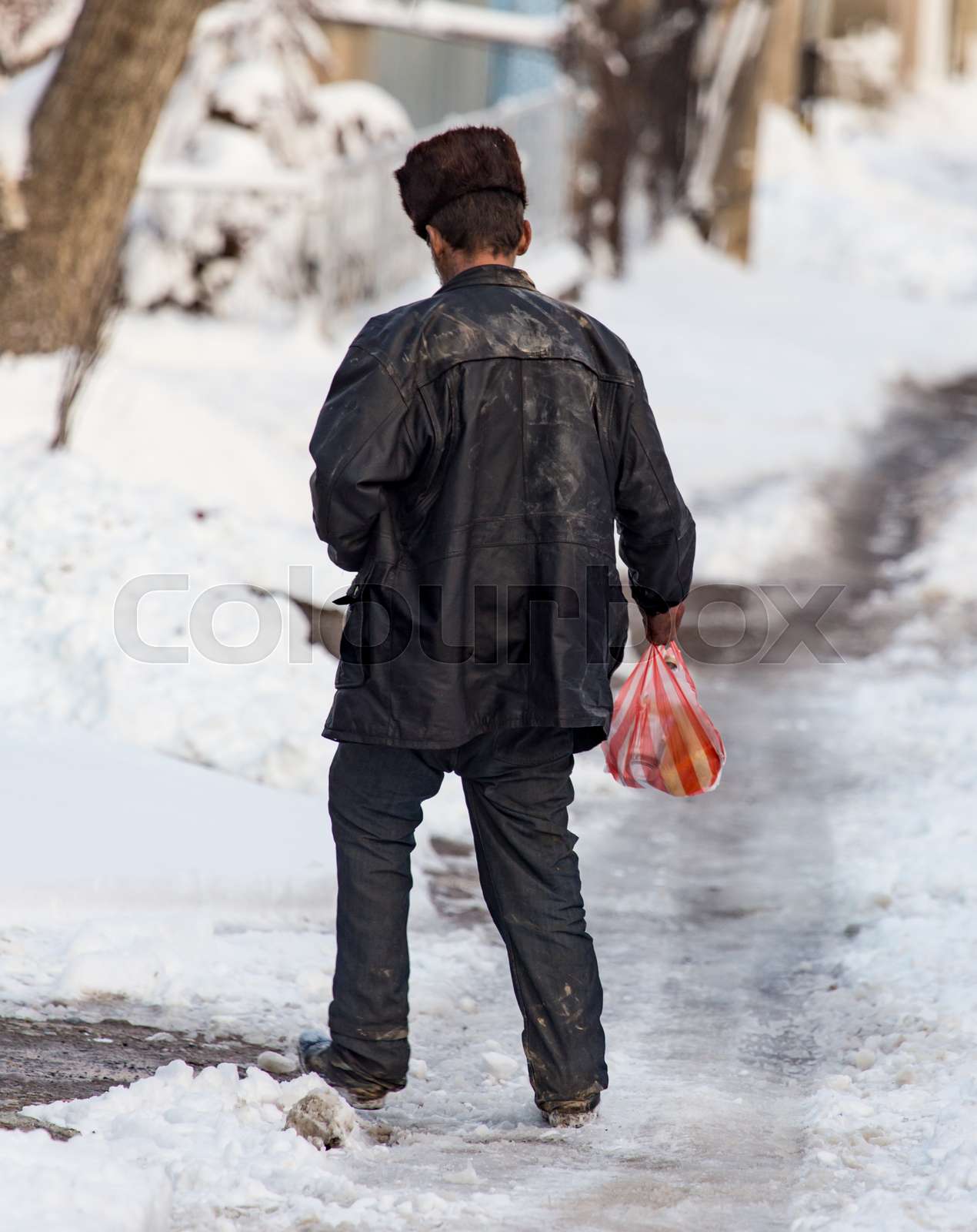 Homeless man is walking on the road in winter | Stock image | Colourbox