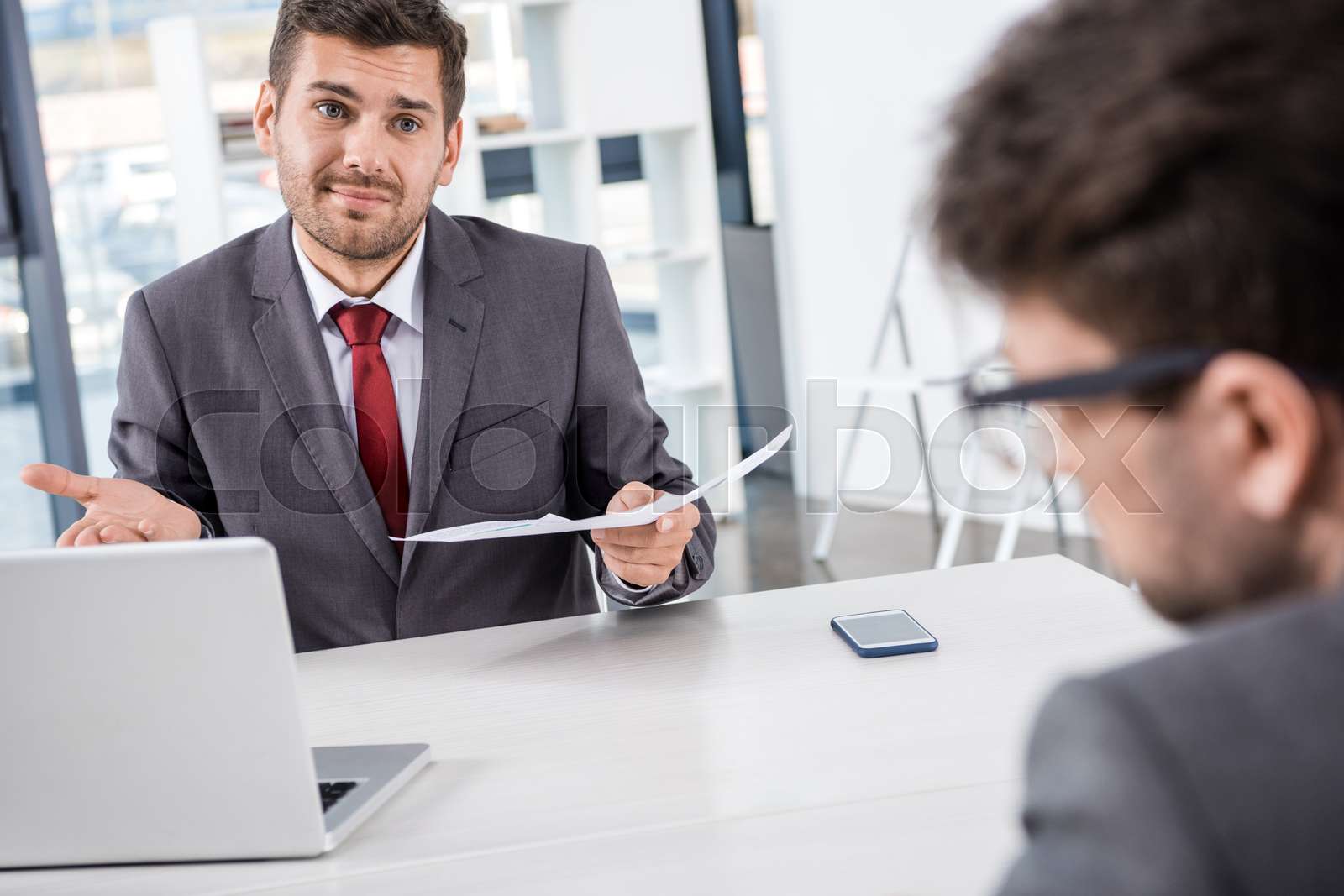 unsatisfied boss with documents looking at colleague at business ...