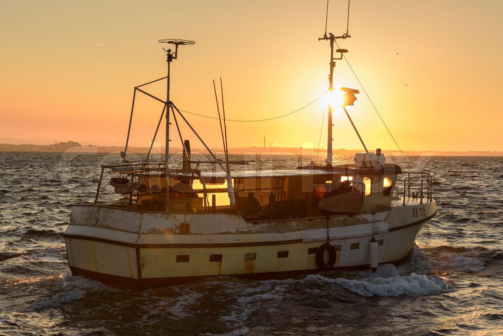 En fiskekutter sejler tidligt om morgenen på havet for at fange fisk ...