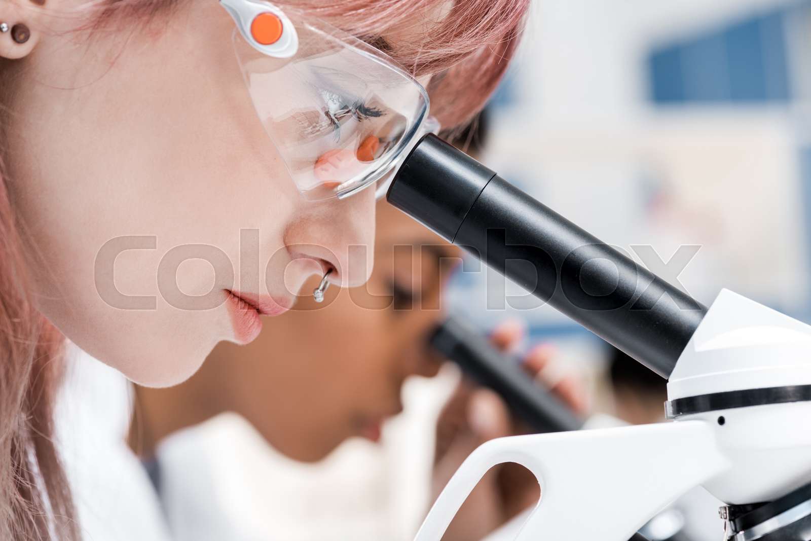 Side view of professional young scientists working with microscopes in ...