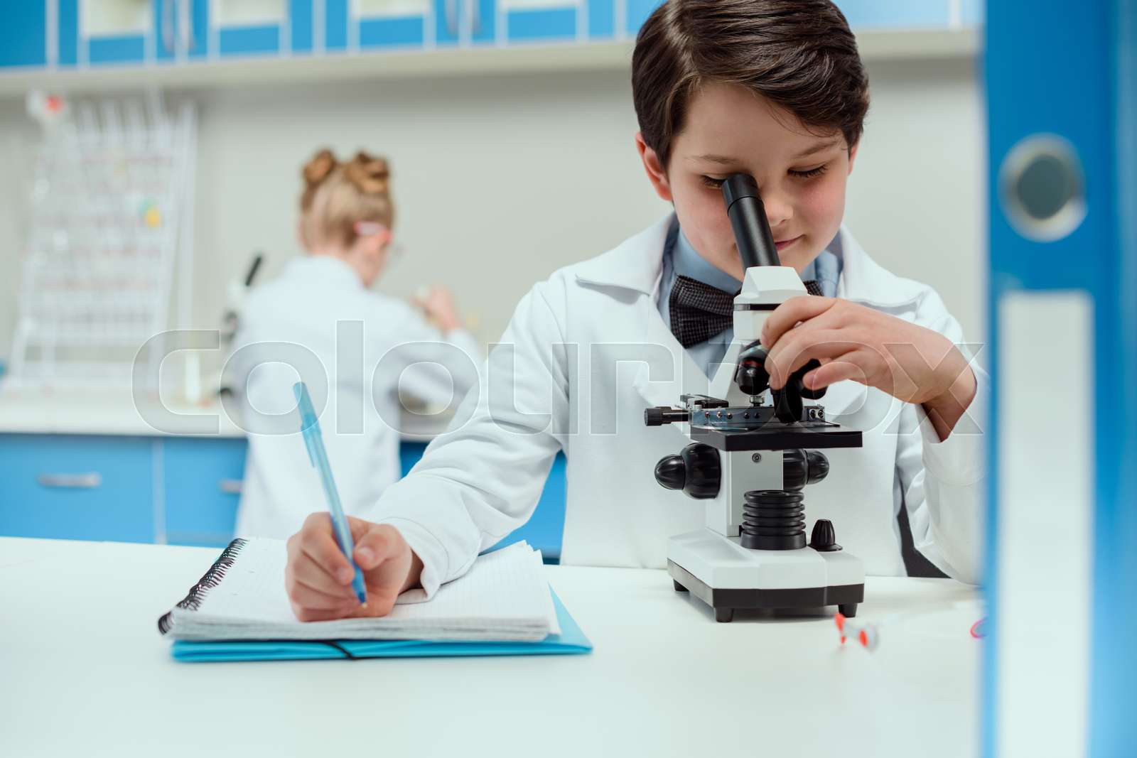 schoolboy with microscope and copybook in science laboratory, science ...
