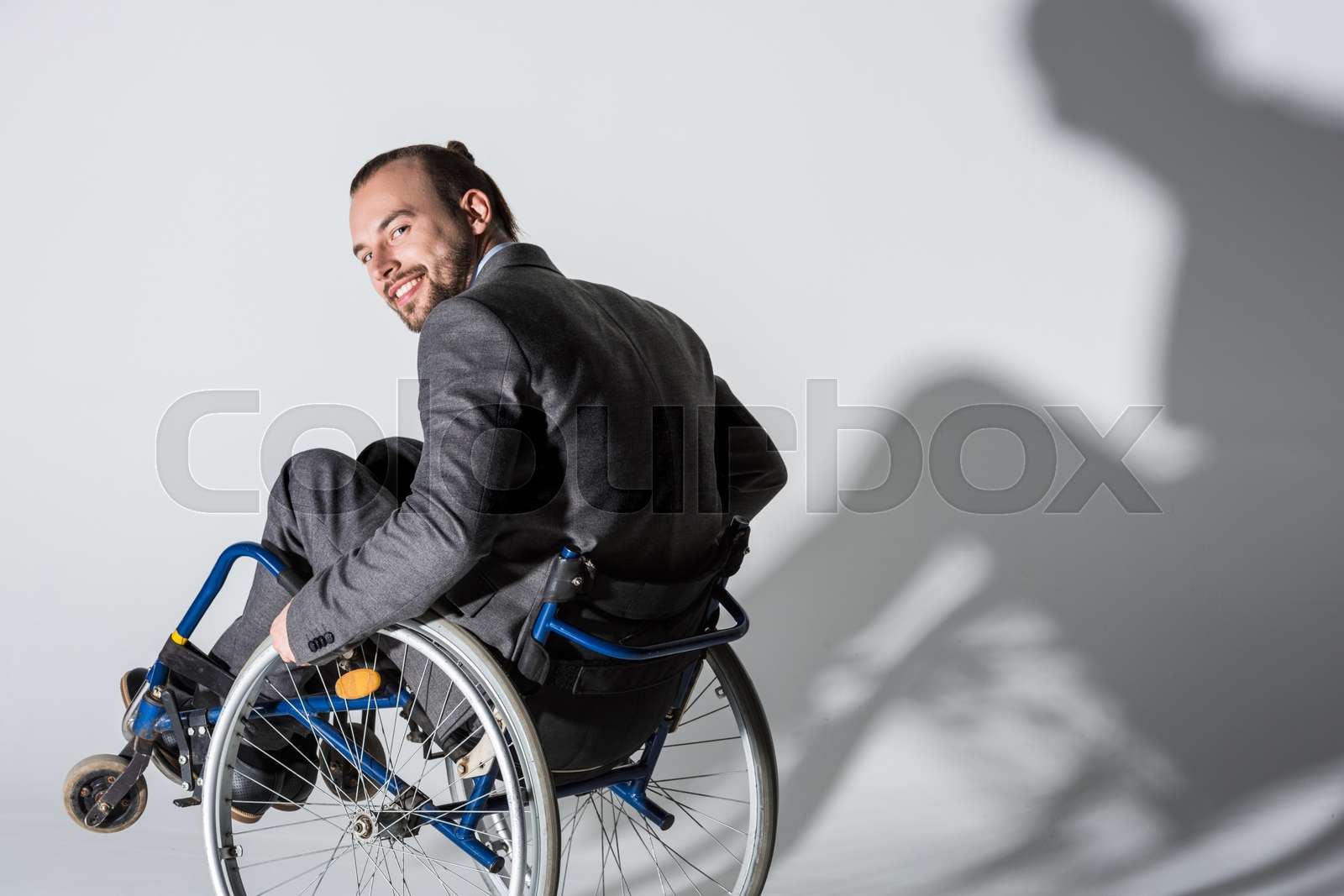 young physically handicapped businessman in wheelchair with his shadow ...