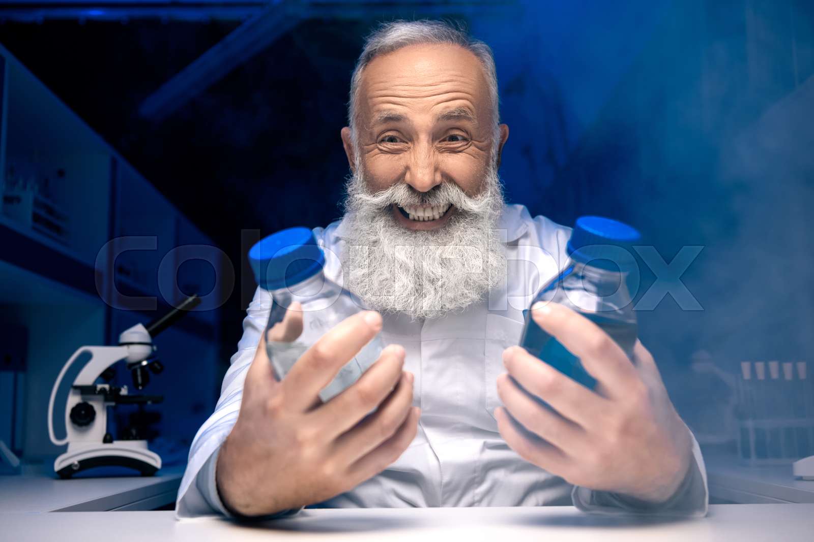 portrait of happy scientist looking at bottles with reagents in hands ...