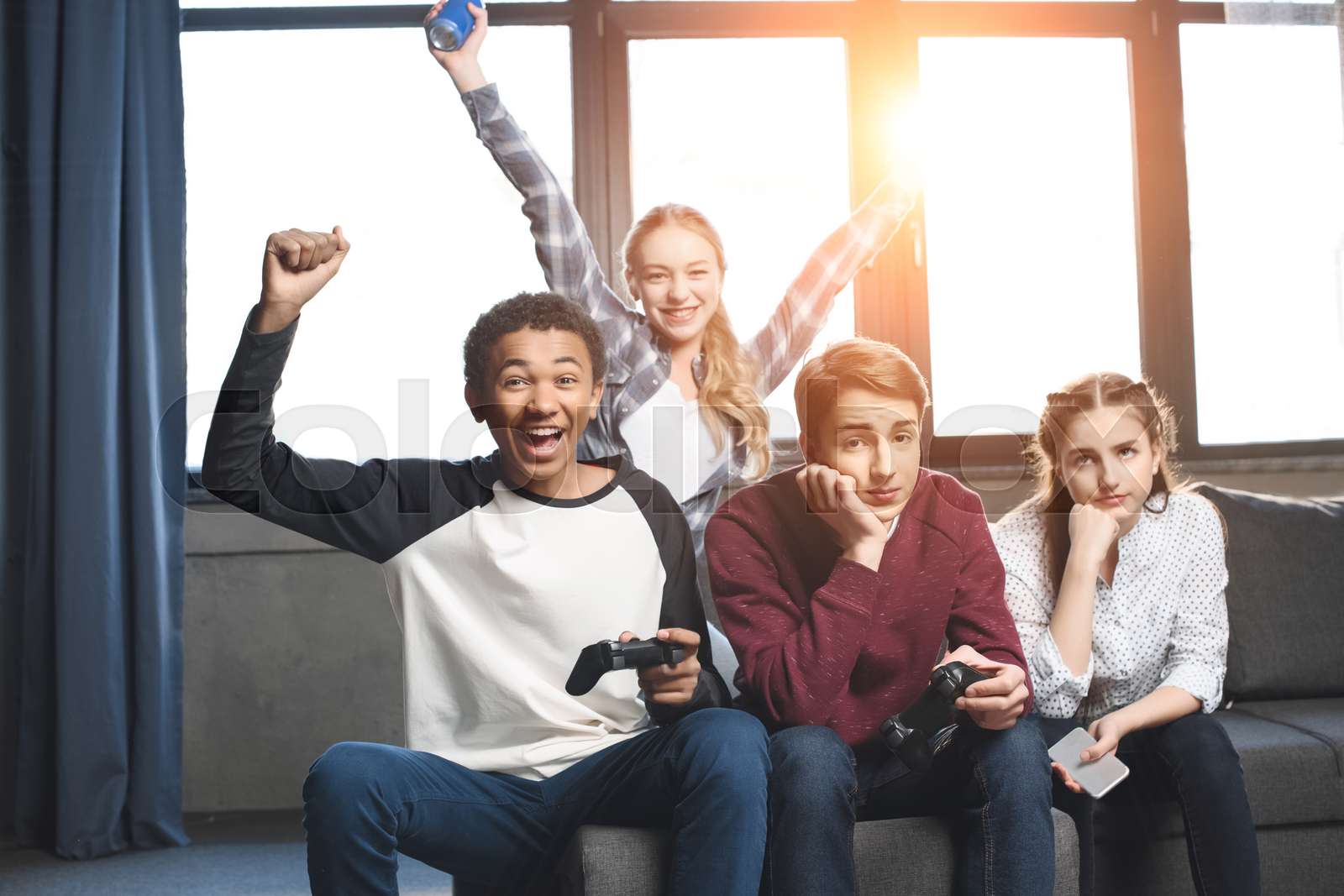 happy multicultural teenagers playing video games with joysticks at ...