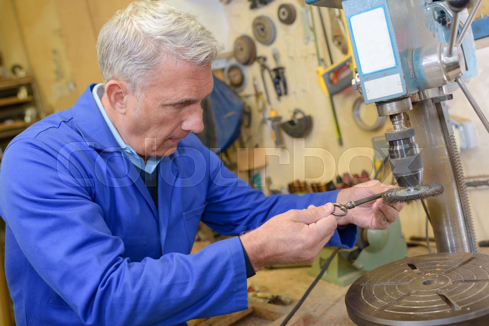 senior locksmith drilling in a key at his workplace | Stock image ...