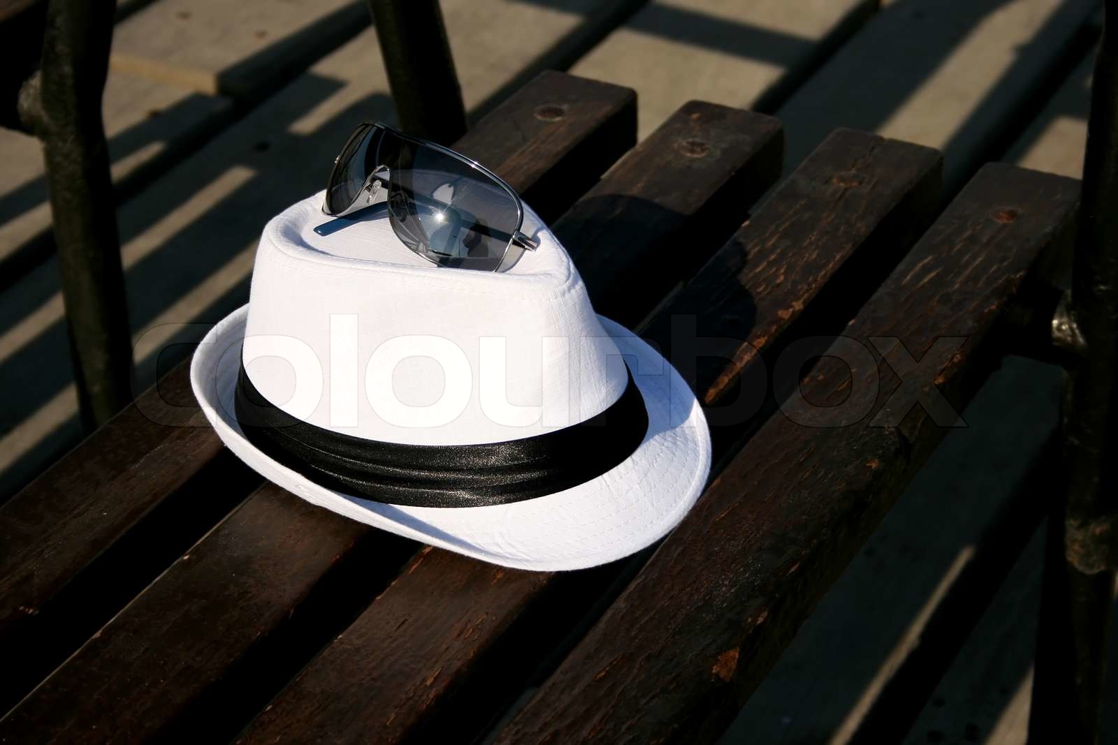 White hat med solbriller på bænk | Stock foto | Colourbox