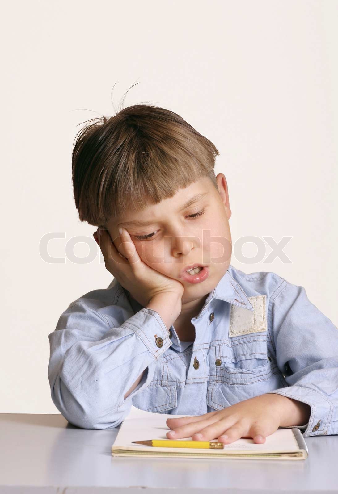 A child sitting at a desk with homework or schoolwork | Stock image ...
