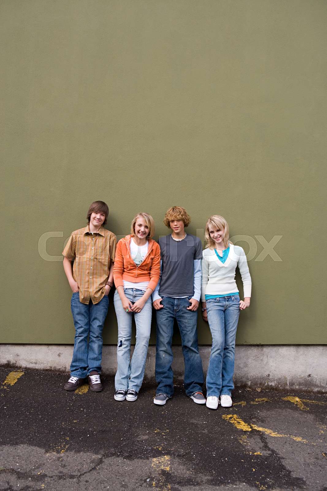 Four teenagers leaning against a wall | Stock image | Colourbox