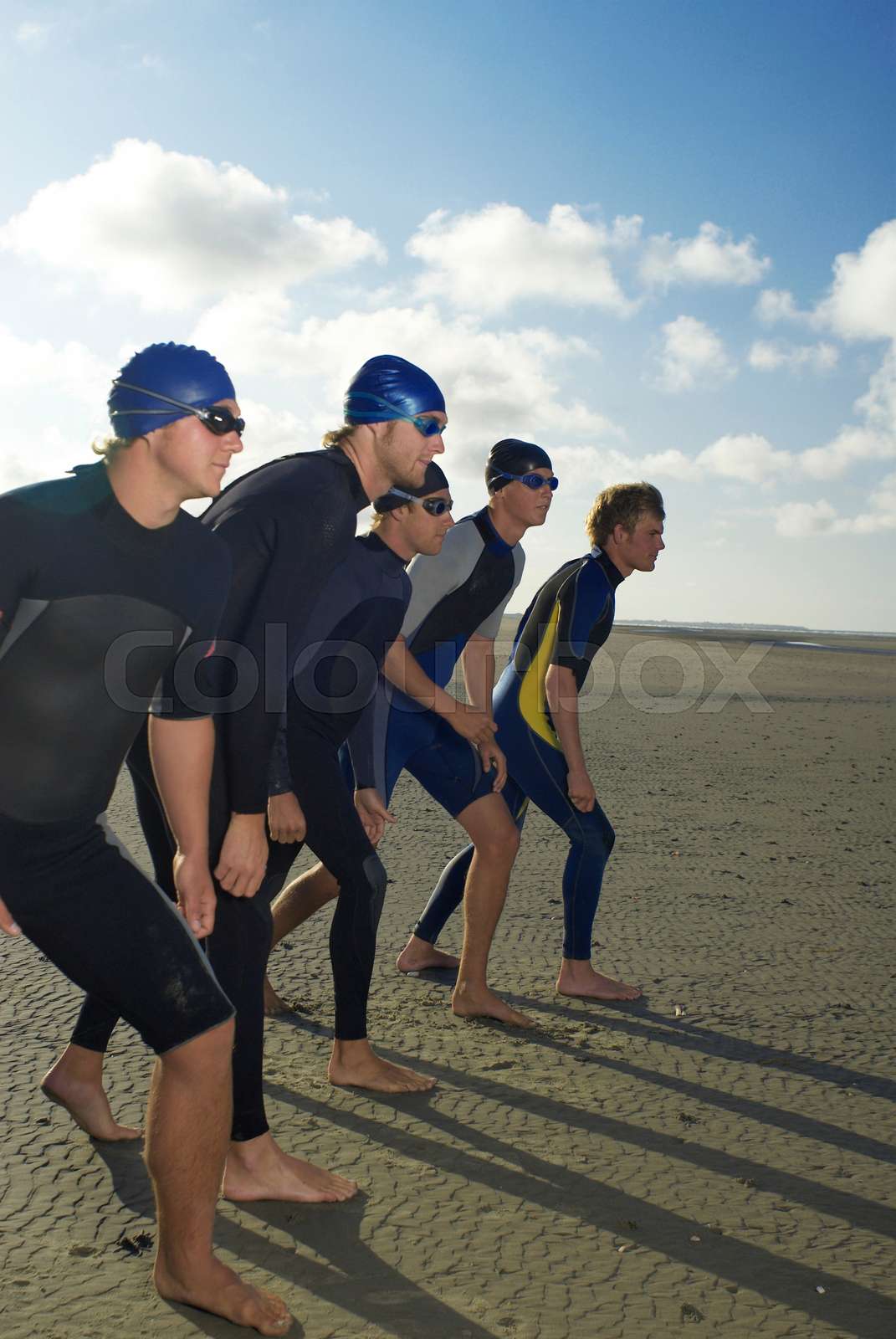 Swimmers standing in row on beach | Stock image | Colourbox