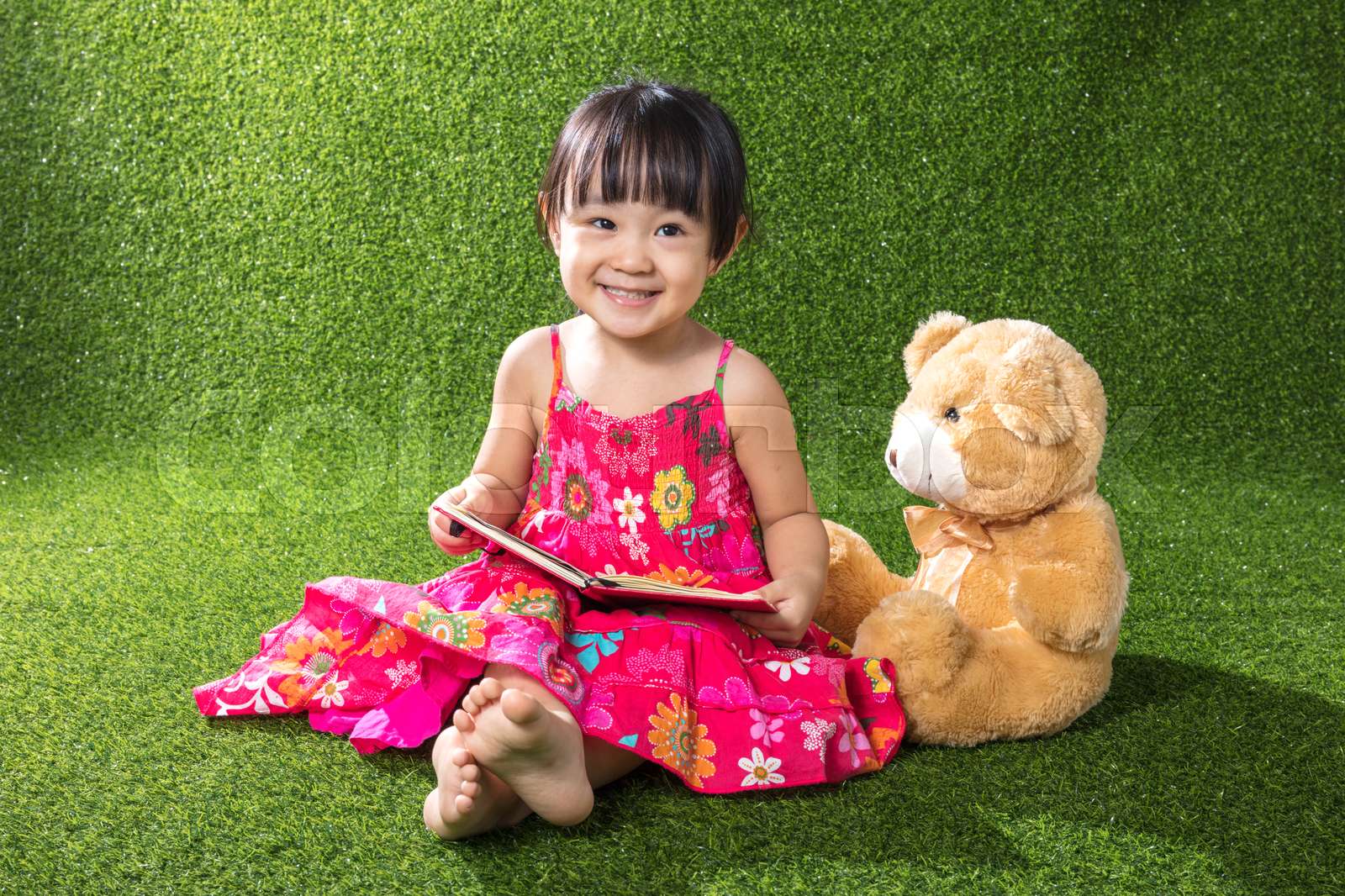 Asian Chinese little girl reading book with teddy bear | Stock image ...