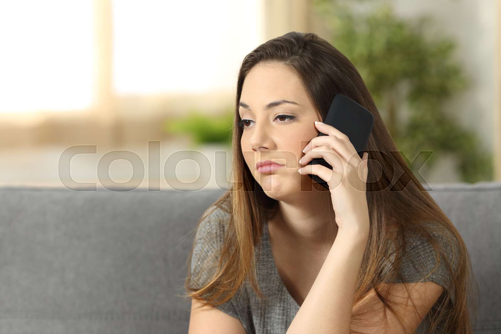 Woman bored during a phone call | Stock image | Colourbox