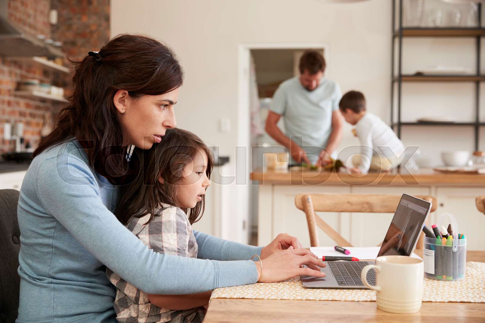 Busy Family Home With Mother Working As Father Prepares Meal | Stock ...