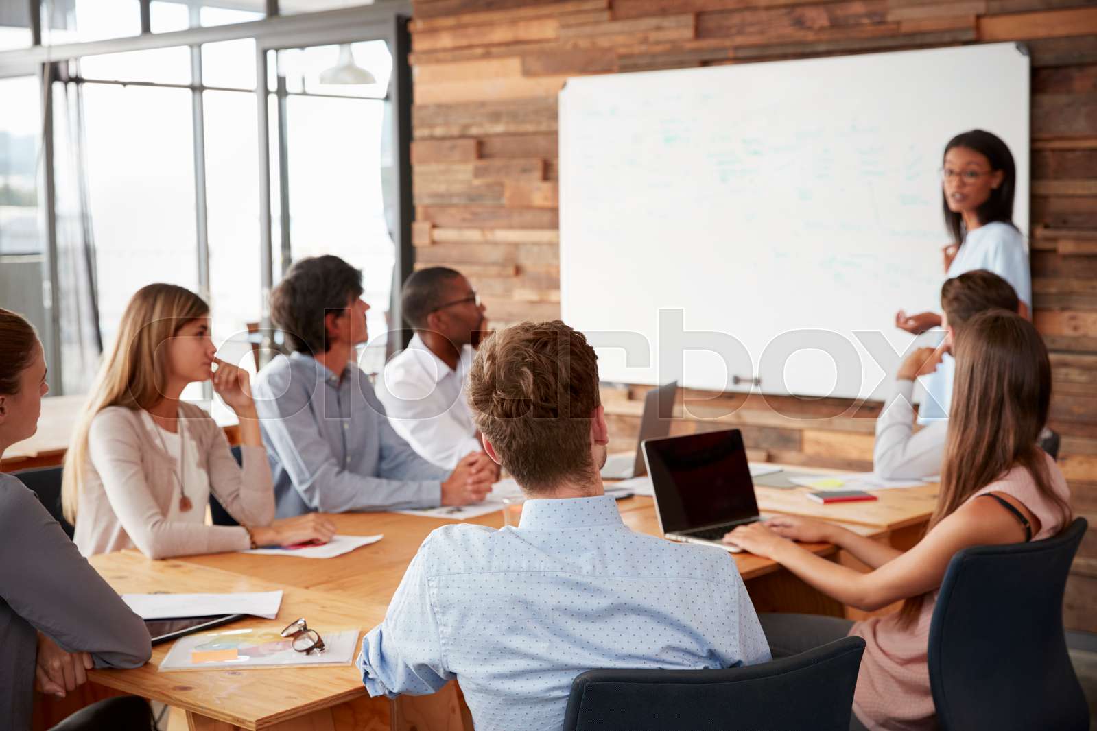 Young black woman presenting to colleagues from whiteboard | Stock ...