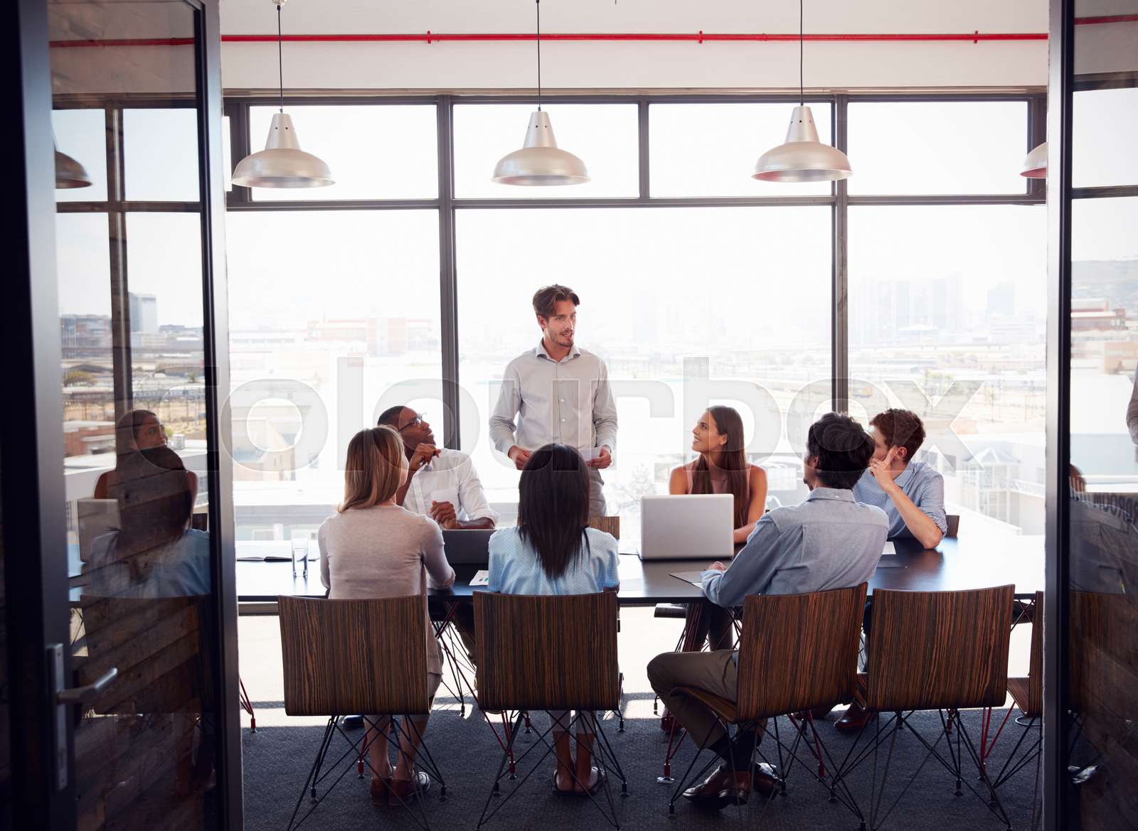 Young man stands addressing team at a meeting in a boardroom | Stock ...
