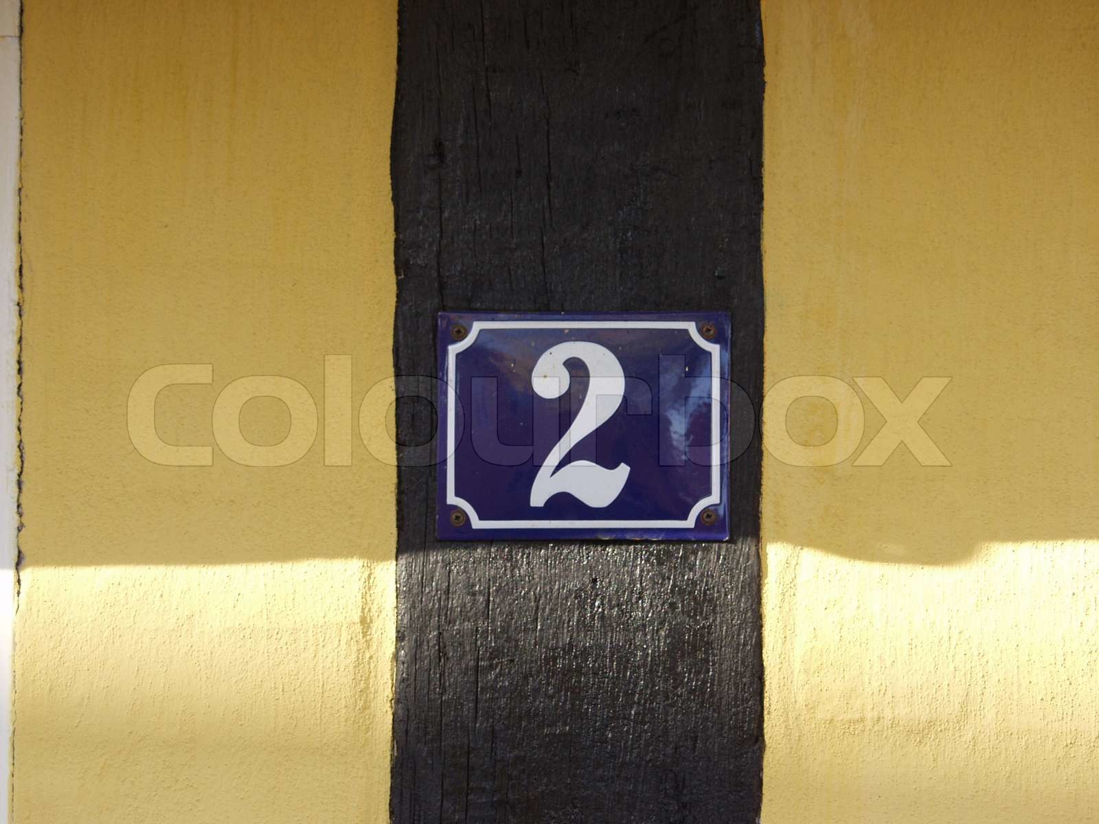 2 tal som husnummer på gul mur | Stock foto | Colourbox