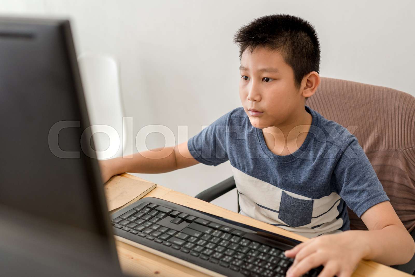 Asian boy playing computer game at home. | Stock image | Colourbox