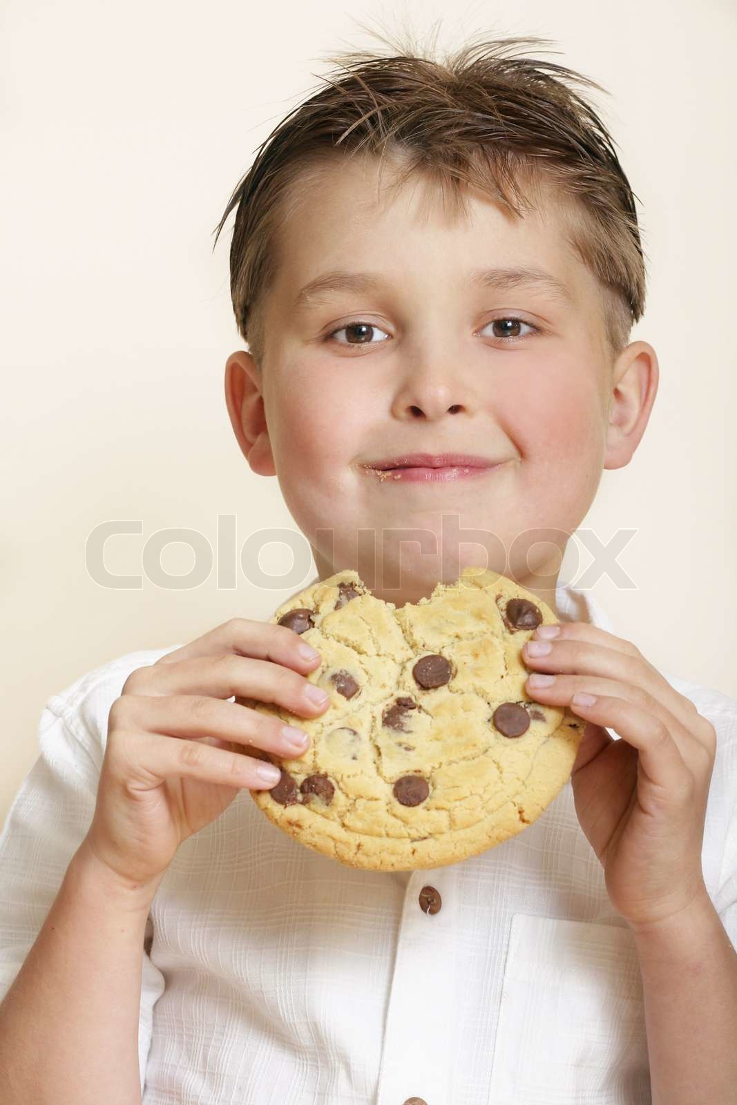 Cute boy boy eating a large cookie and smiling | Stock image | Colourbox