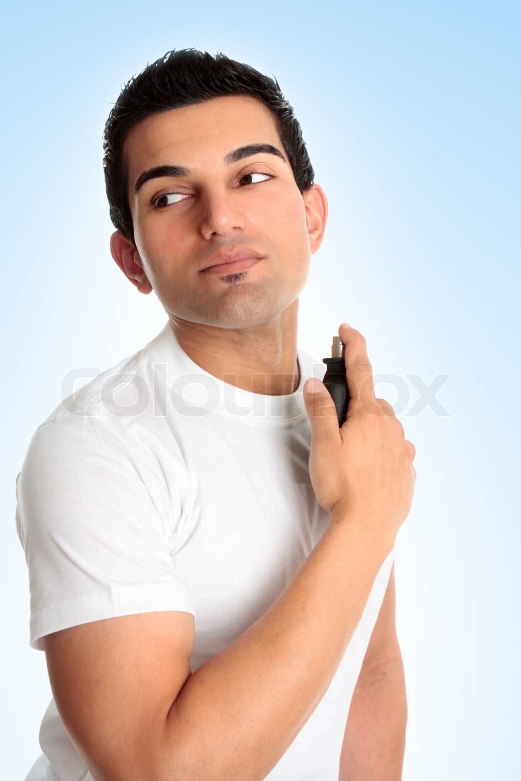A guy holding and spraying a bottle of aftershave cologne perfume ...