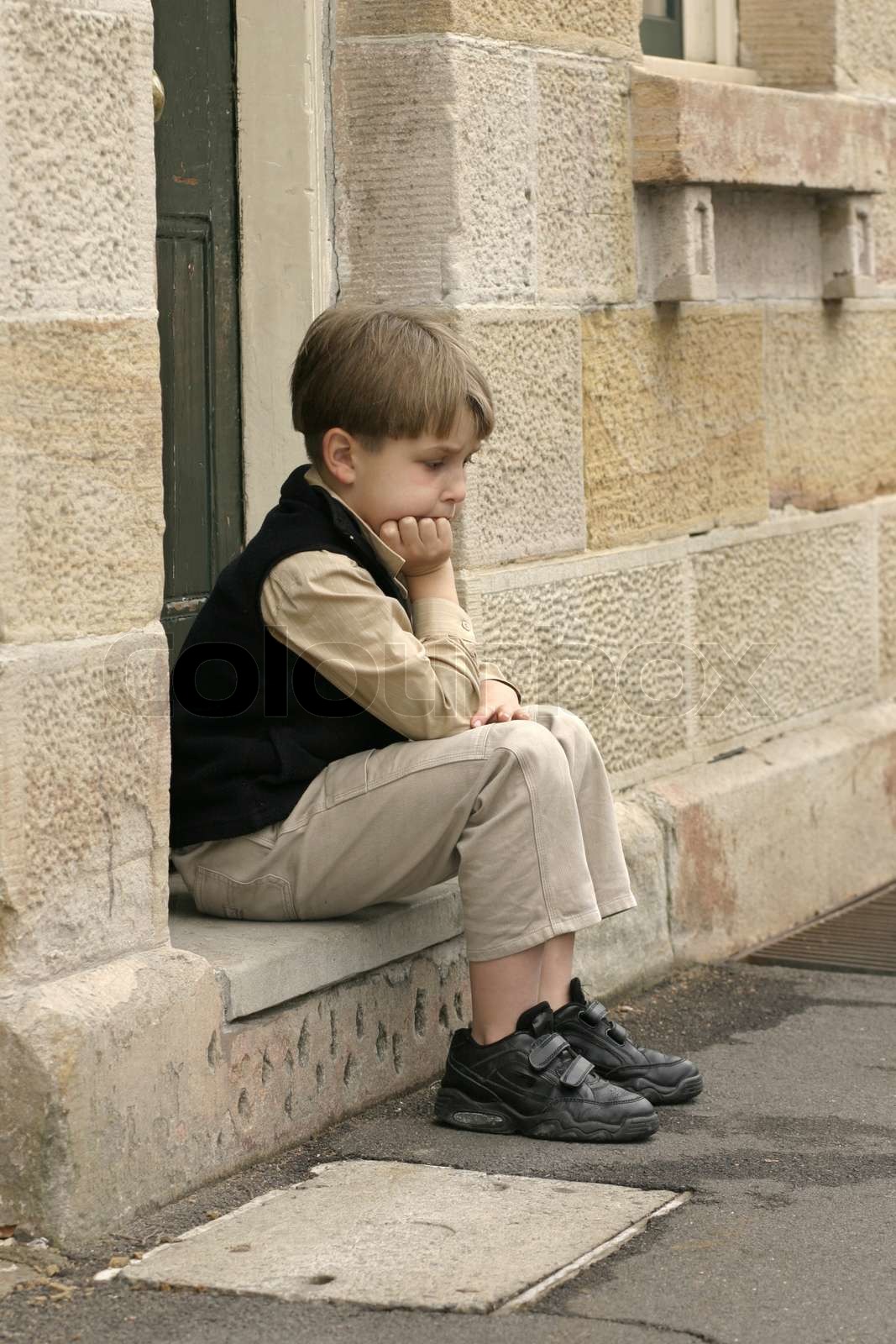 Young boy sitting on the doorstep Feeling a little glum, sad, lonesome ...