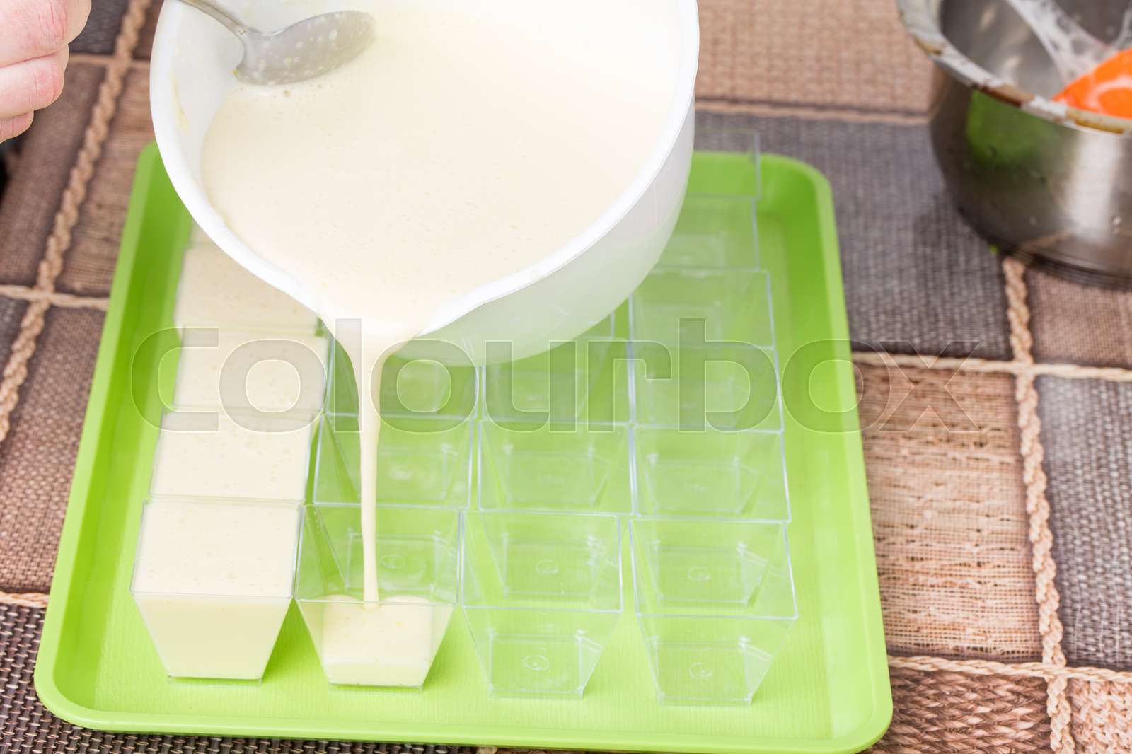 Pouring dough into plastic baking forms. | Stock image | Colourbox
