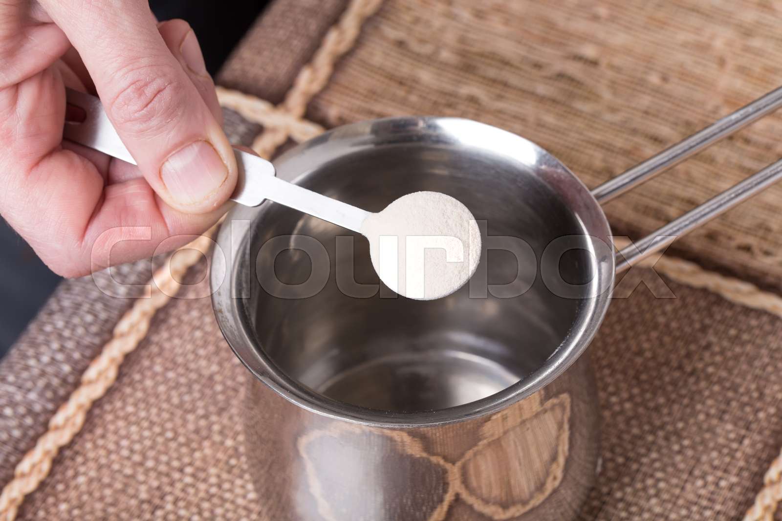 Adding powdered gelatin to water. | Stock image | Colourbox