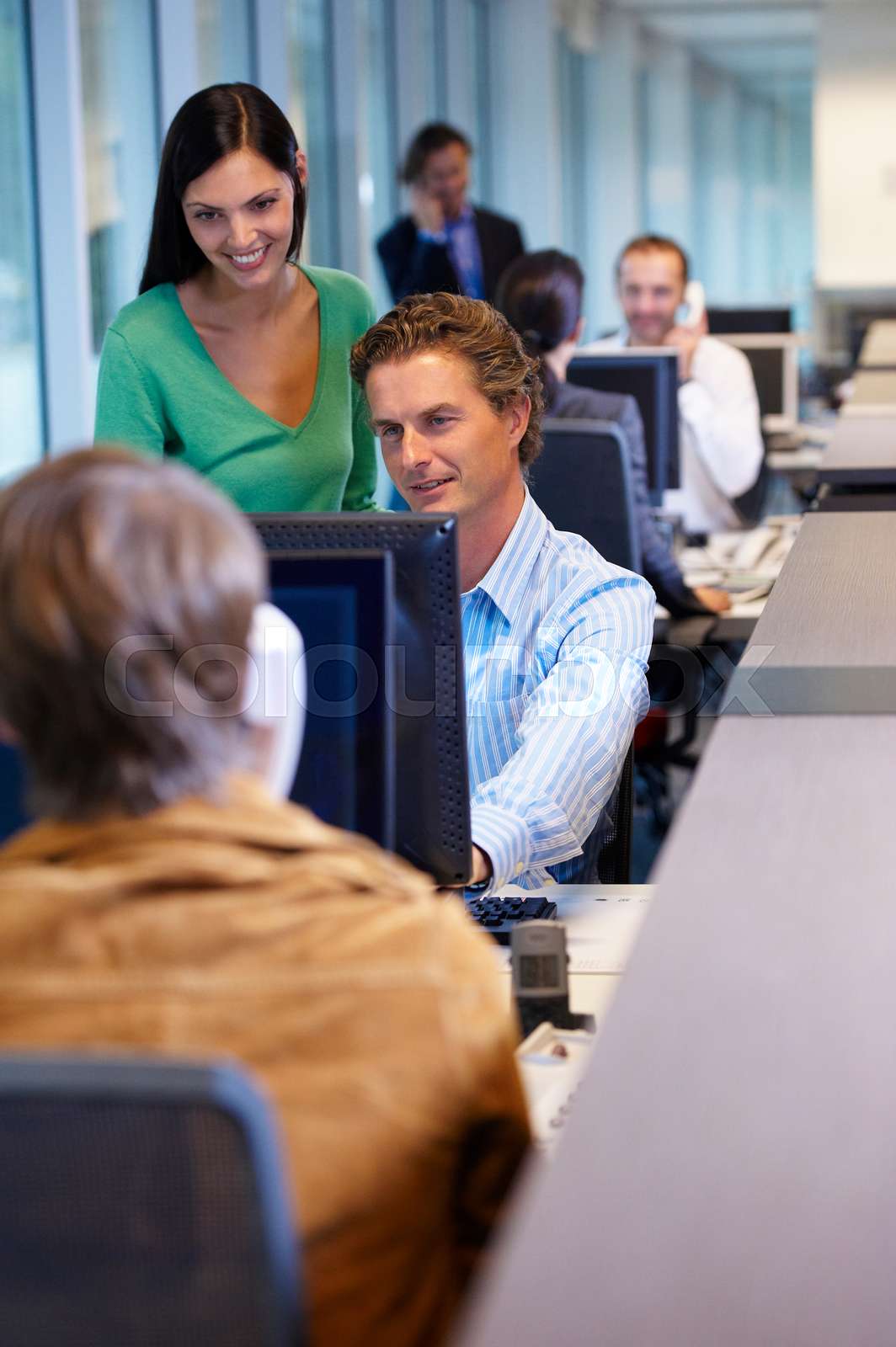 Office workers looking at a computer | Stock image | Colourbox