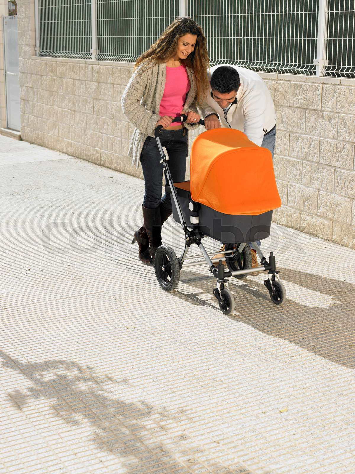 Couple looking into pram on pavement | Stock image | Colourbox