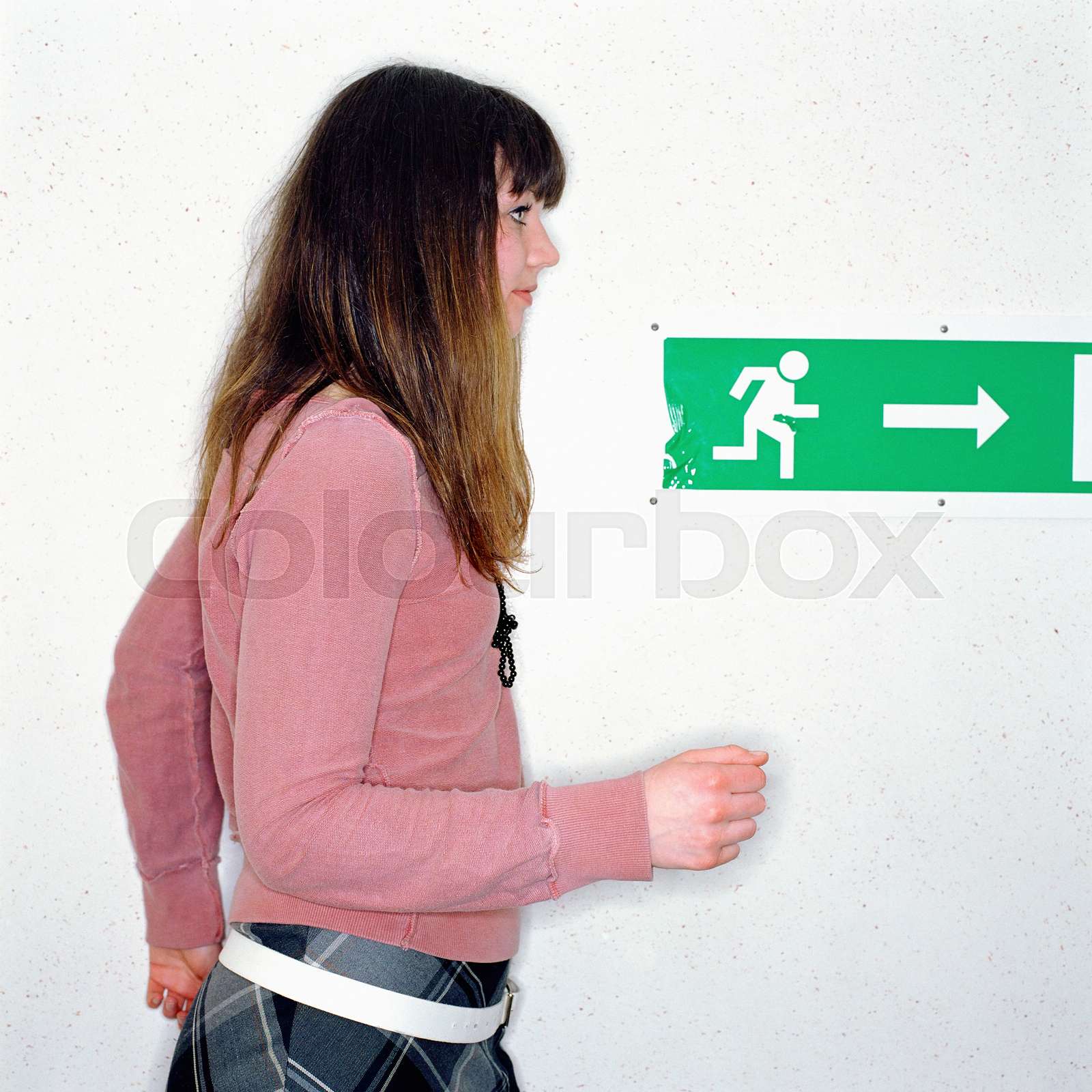 Girl walking past exit sign | Stock image | Colourbox