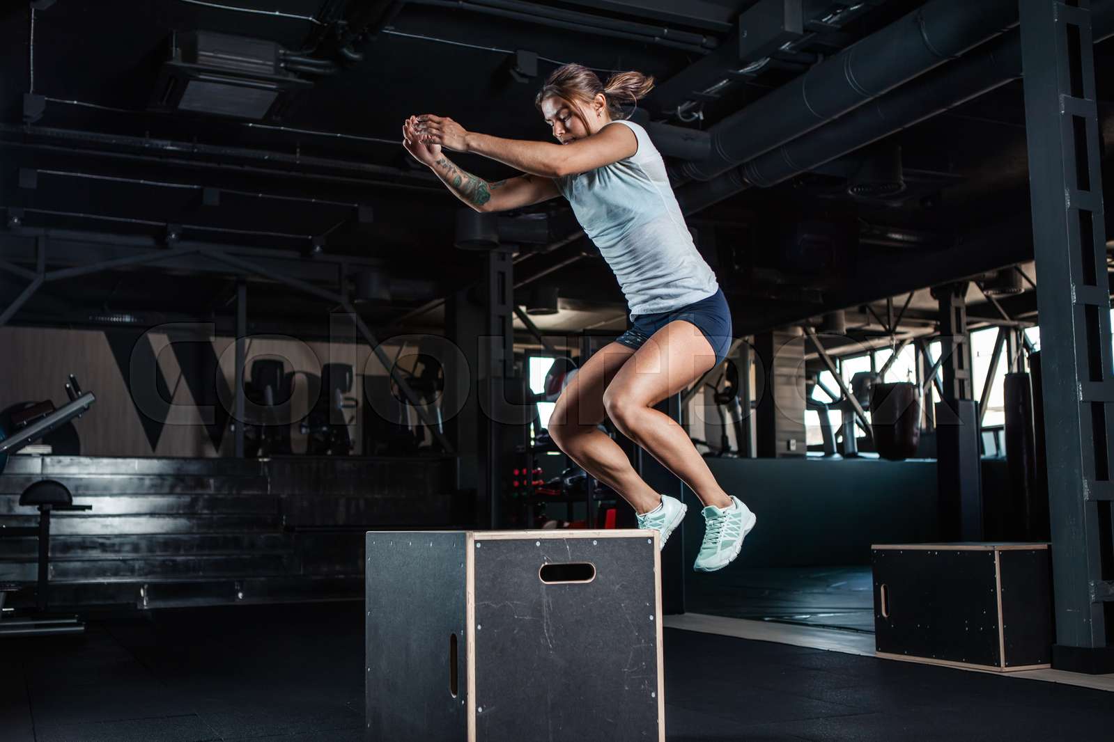 Sporty girl jumping over some boxes in gym | Stock image | Colourbox