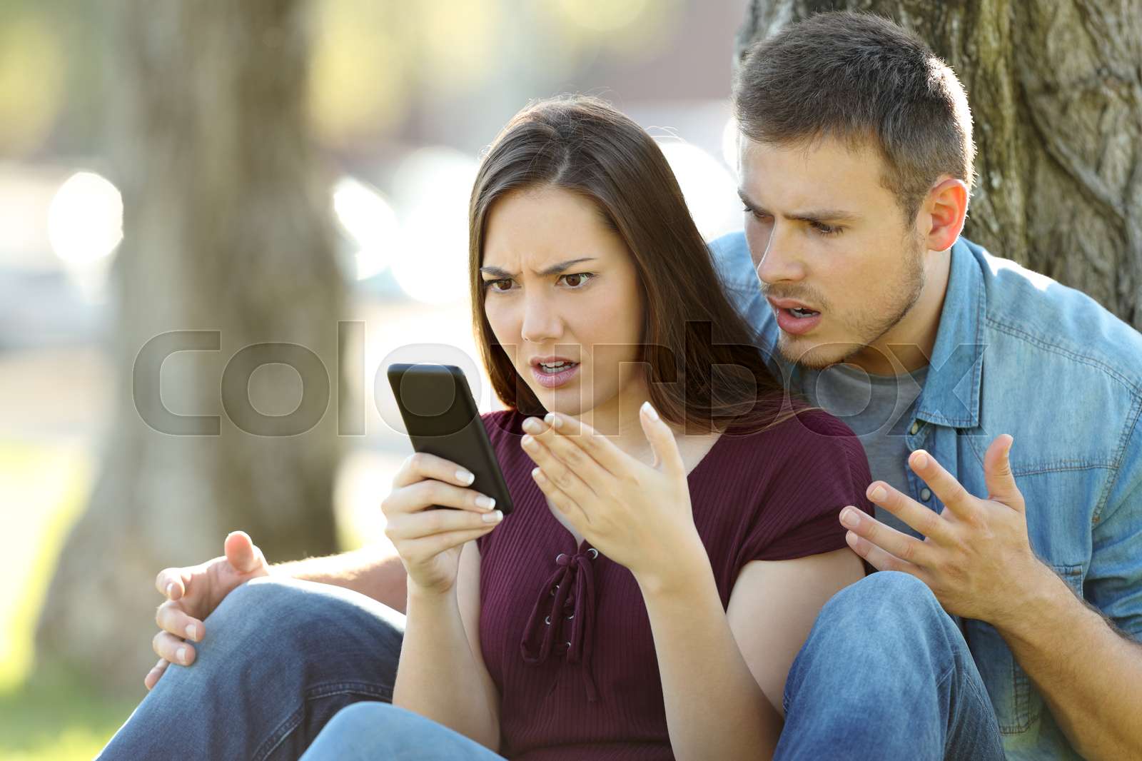 Angry couple using a smart phone outdoors | Stock image | Colourbox
