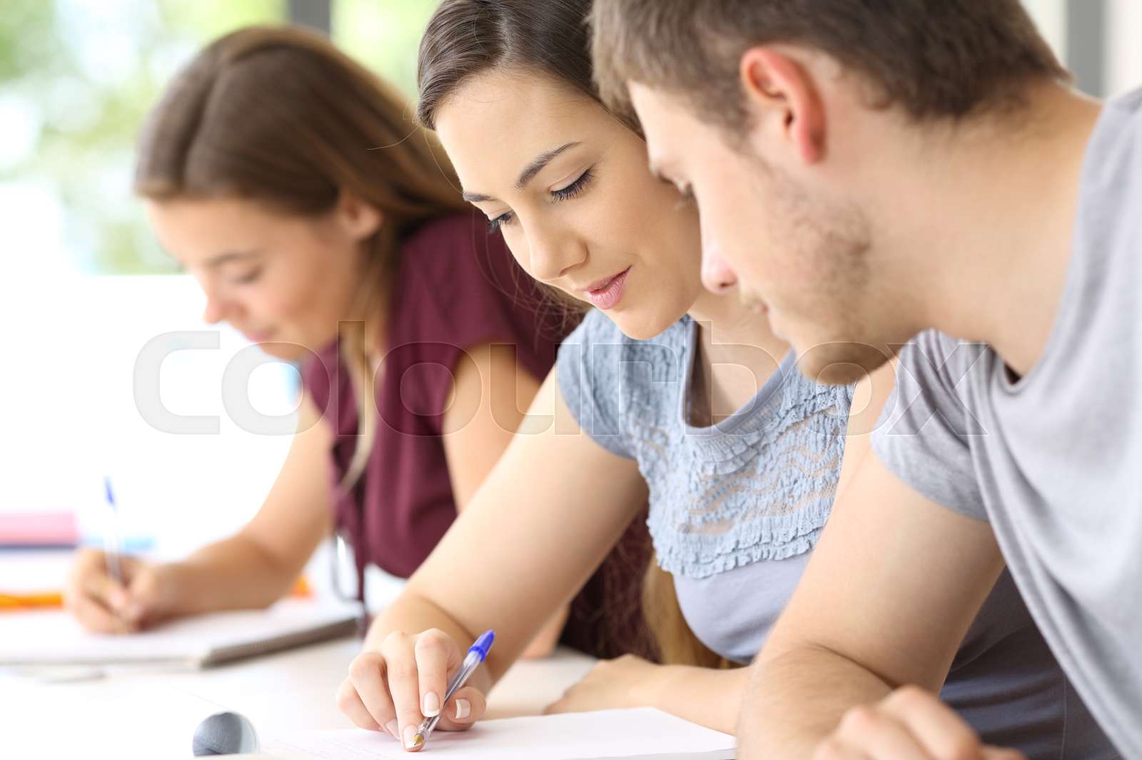 Student helping to a classmate at classroom | Stock image | Colourbox