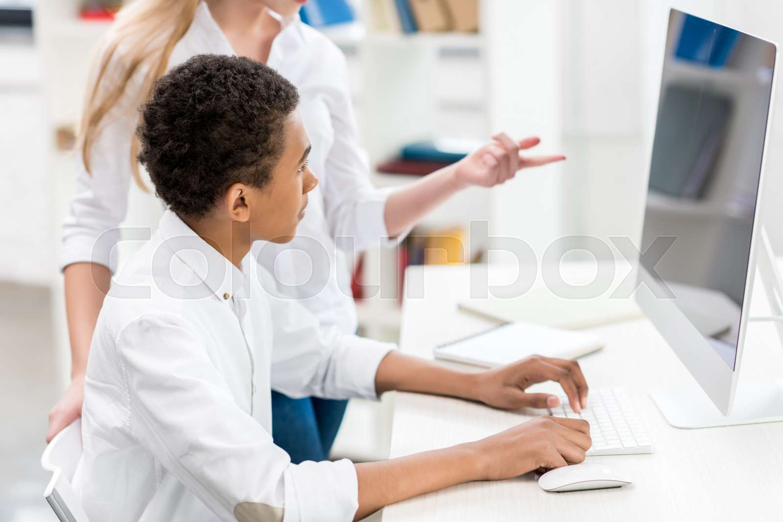multicultural students discussing task at computer screen in class ...