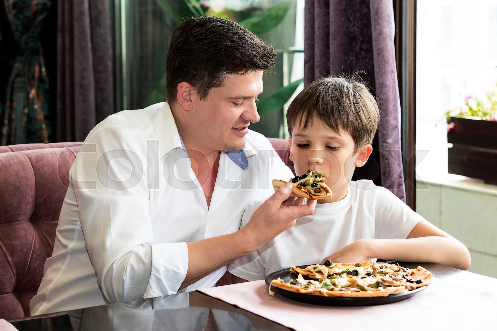 Father son eating an Italian pizza at a pizzeria | Stock image | Colourbox
