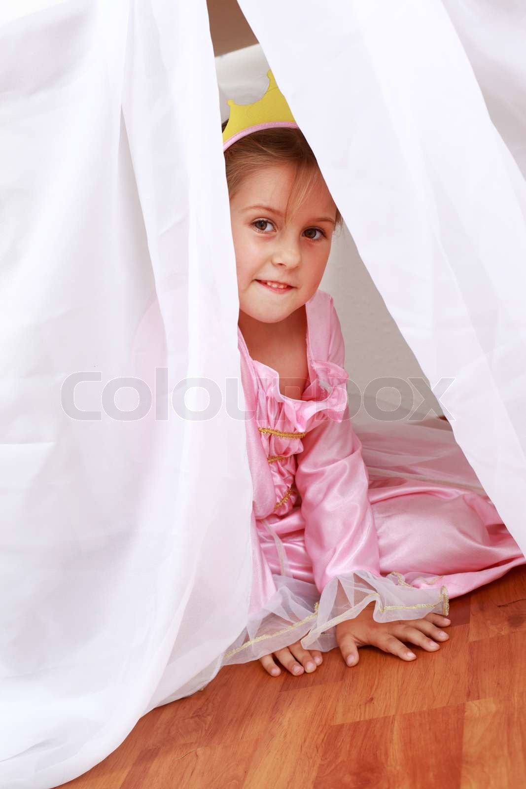 Adorable girl dressed as princess playing hide-and-seek at home | Stock ...