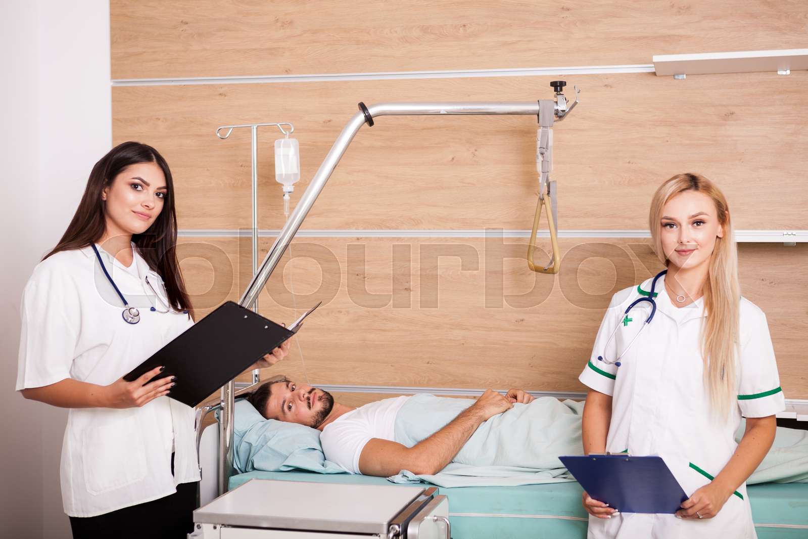 Patient in hospital room next to two nurses | Stock image | Colourbox