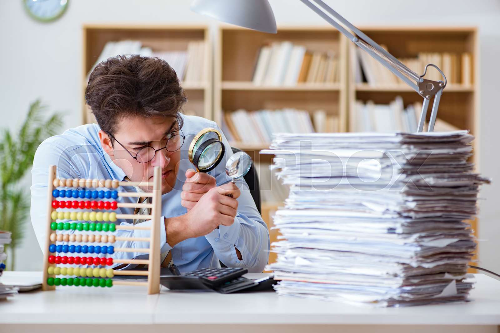Mad auditor looking for errors in the report | Stock image | Colourbox