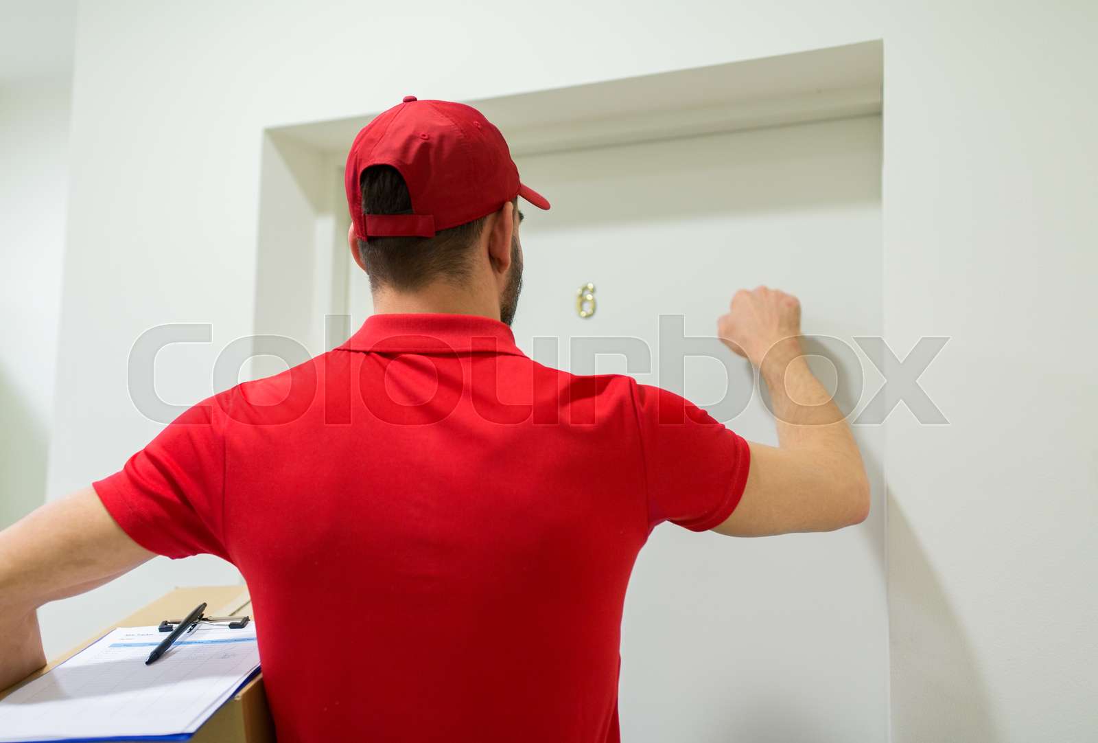delivery man with parcel box knocking door | Stock image | Colourbox